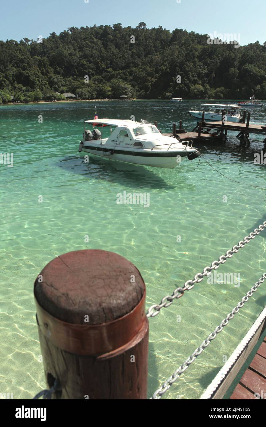 A tourist boat on the coastal water, seen from a jetty on Pulau Sapi ...