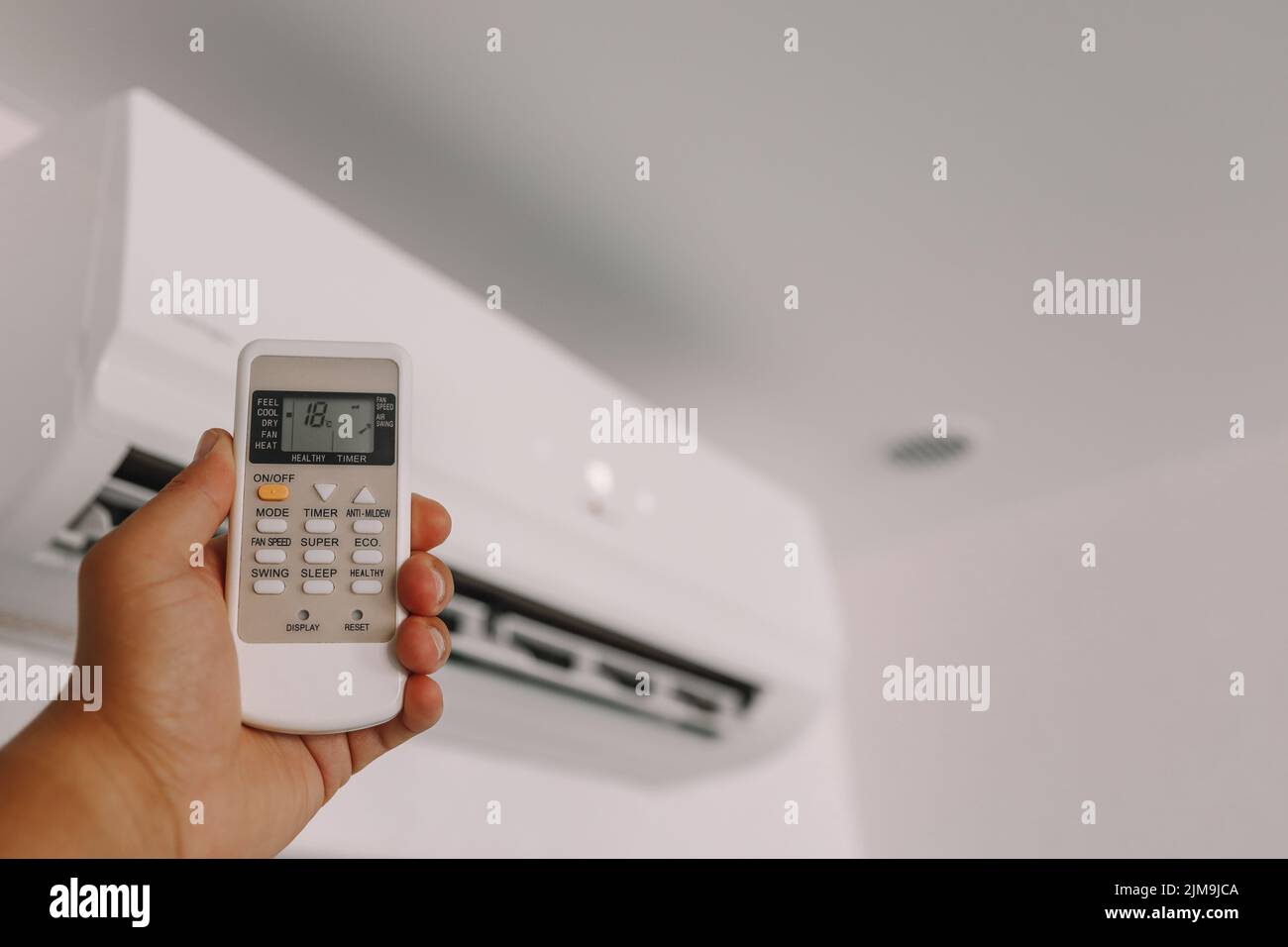 Hand is holding a remote control of air conditioner Stock Photo - Alamy