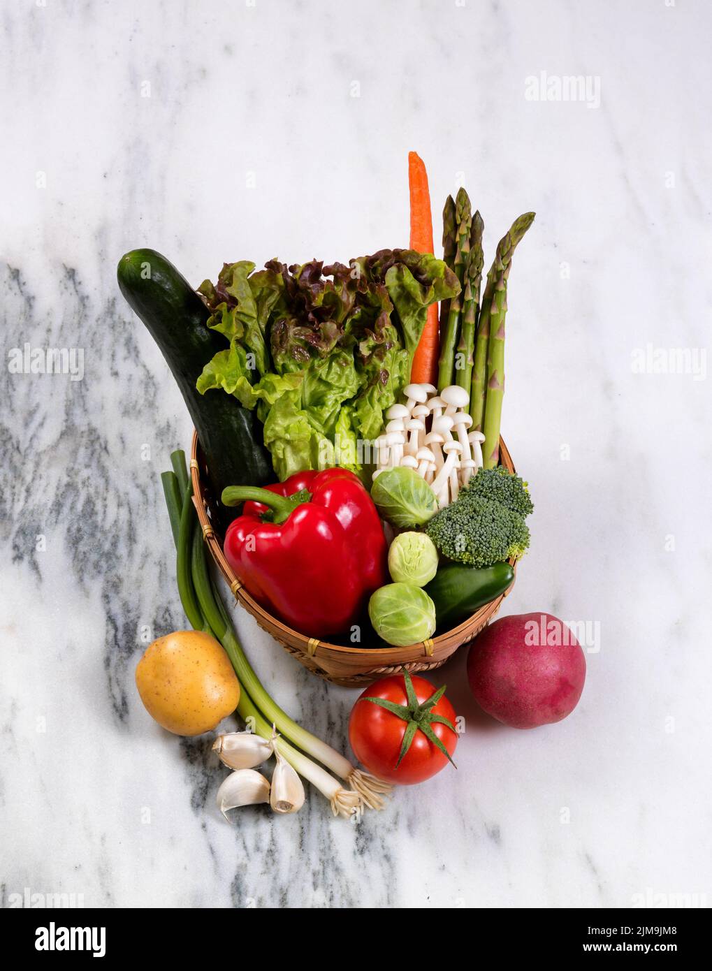 Basket of fresh whole vegetables displayed on natural marble stone ...