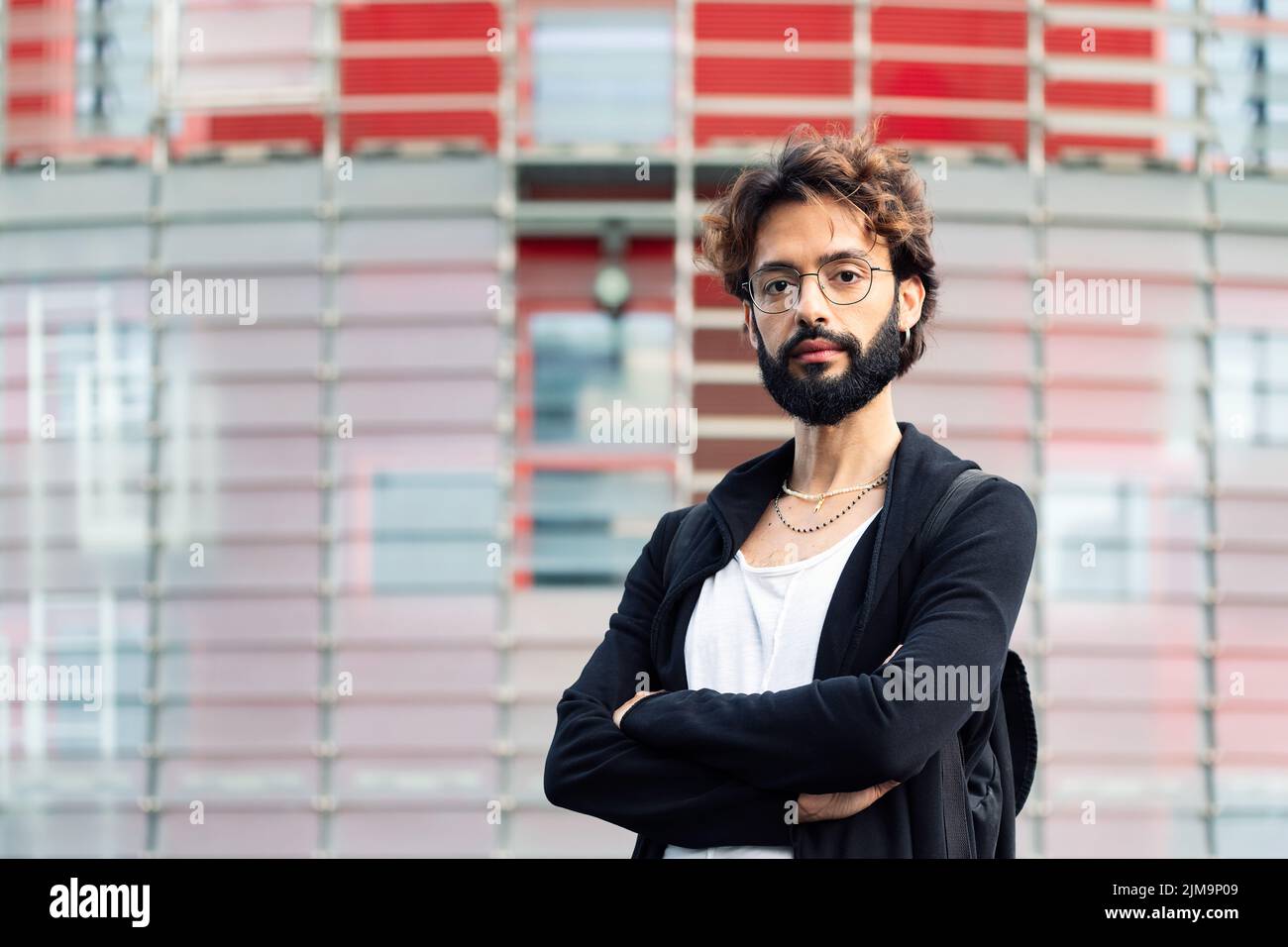 portrait of a young student with glasses and beard with arms crossed ...