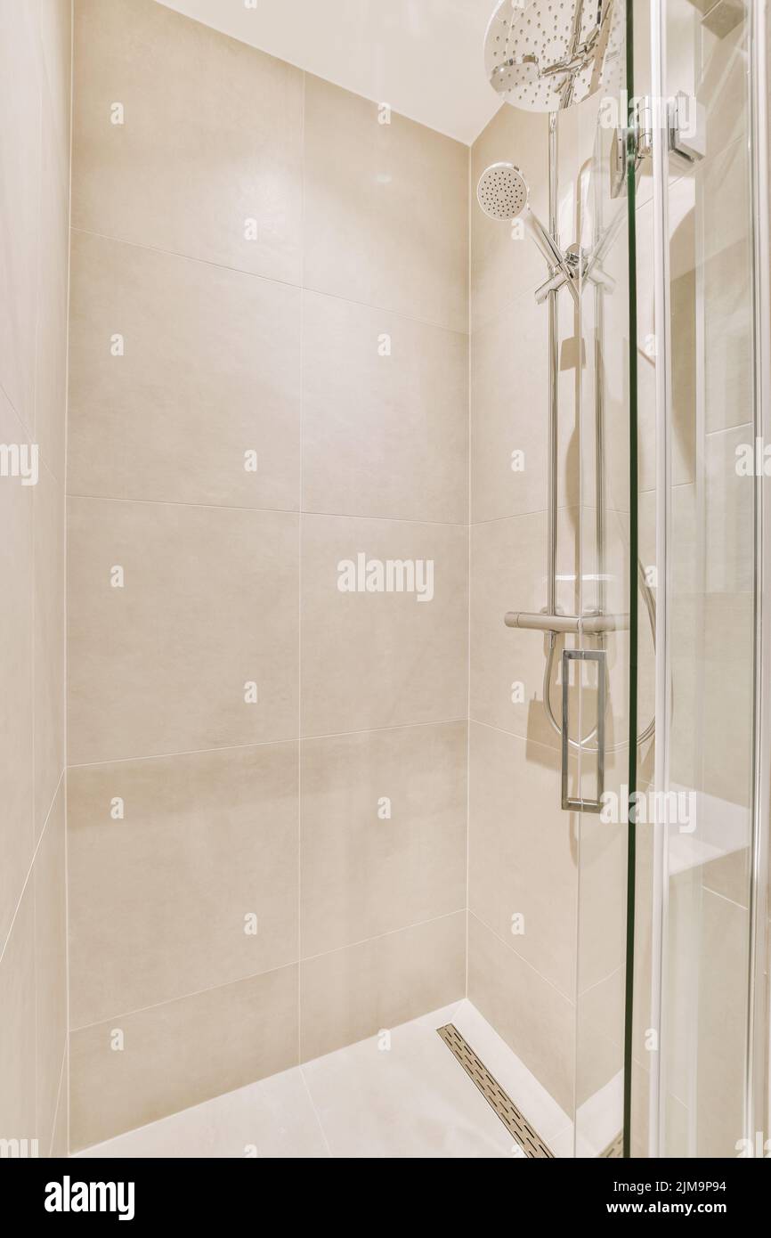 Shower faucets attached to tiled wall near glass partition and ...