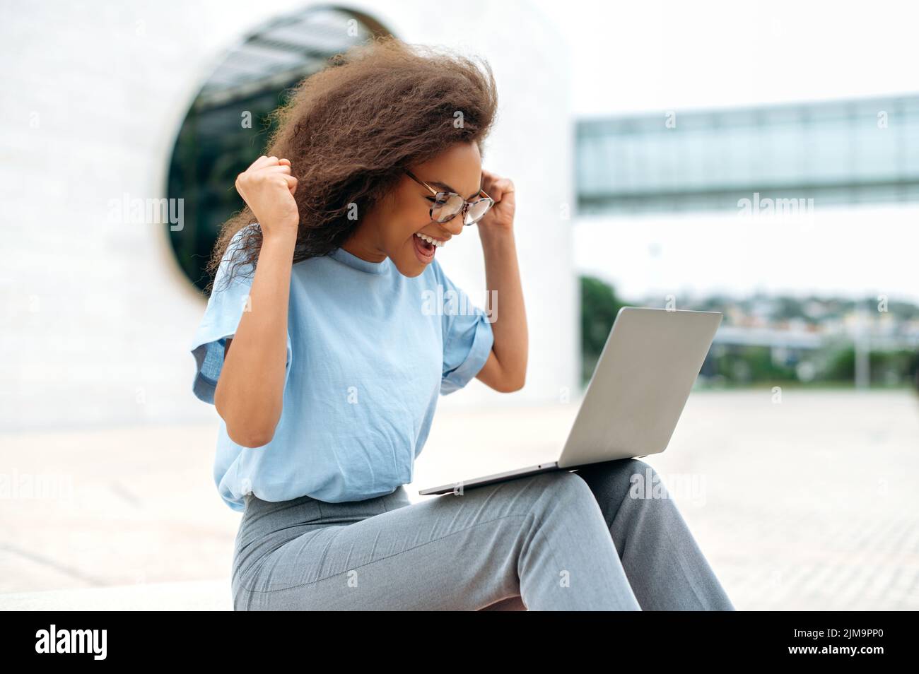 Emotional cheerful african american young woman with glasses, uses ...
