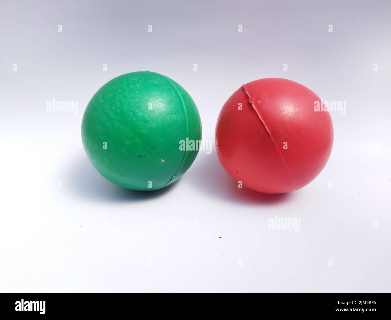 A couple of small, green and red plastic balls with a white background ...