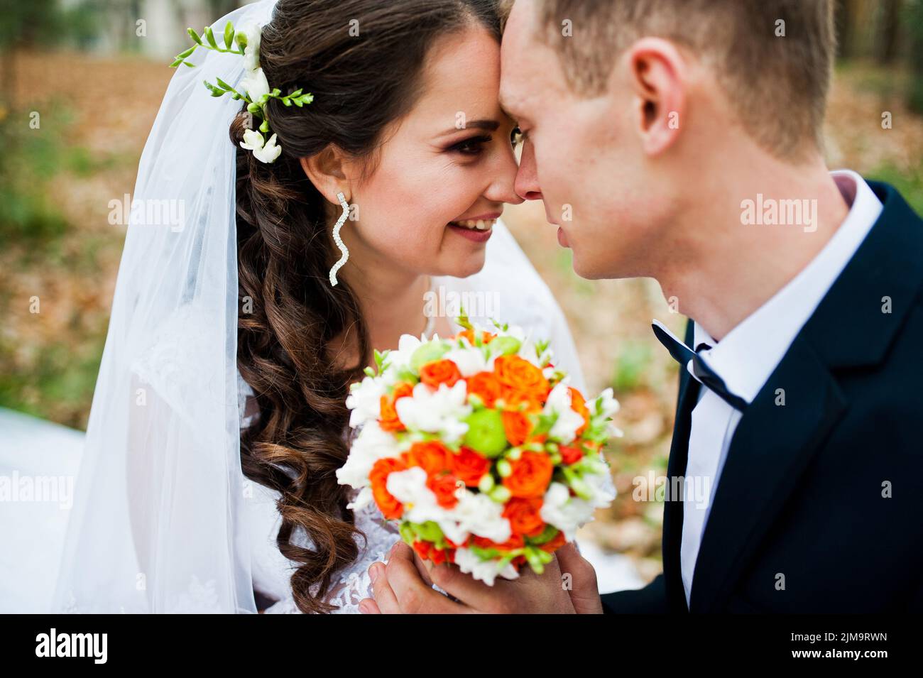 Very close up look of bride and groom with small orange wedding bouquet ...