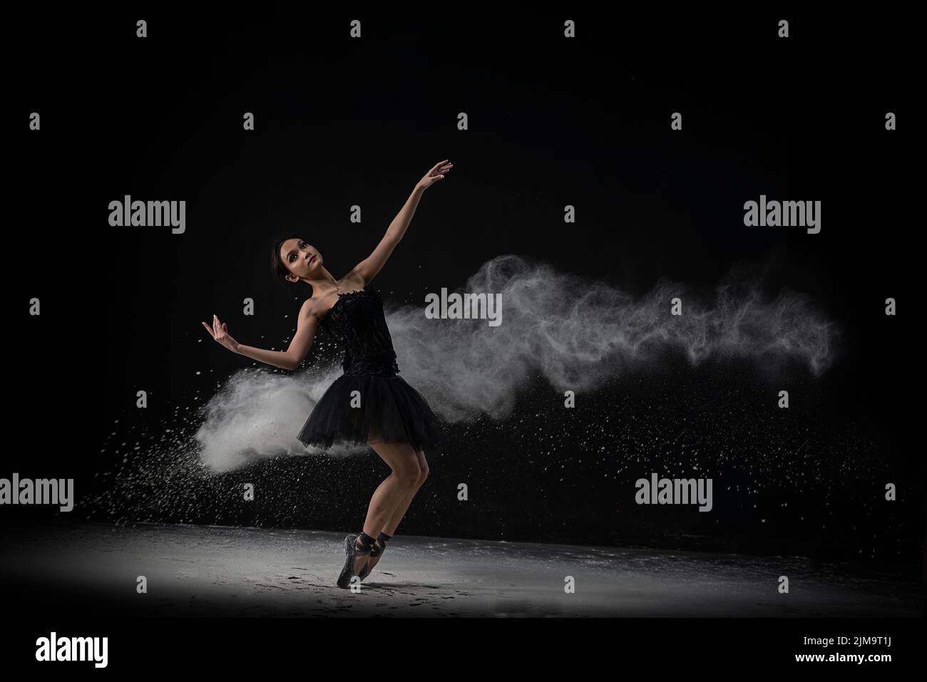 An emotional Southeast Asian ballet dancer in a black dress with powder ...