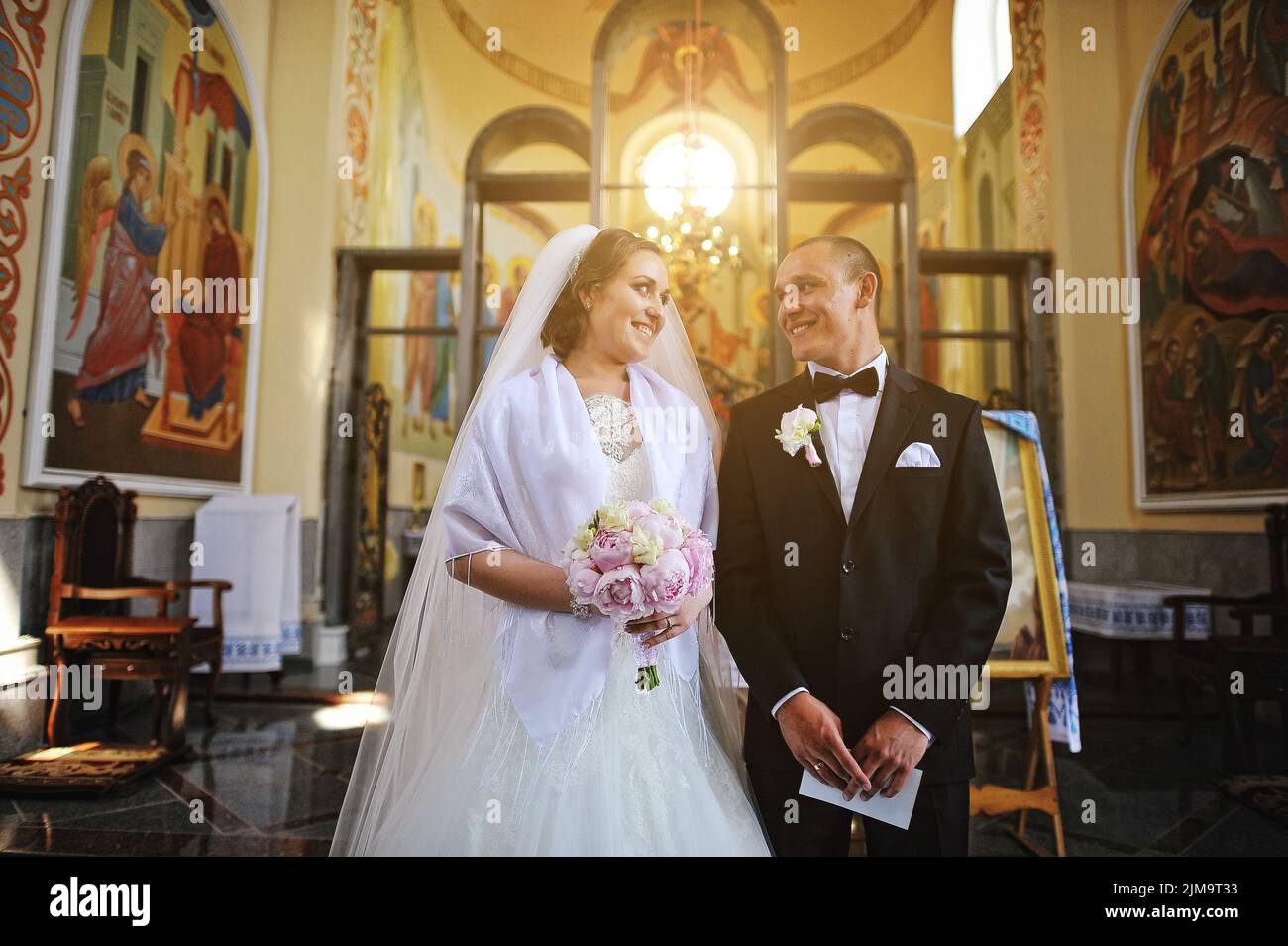 Happy wedding couple stay at church and looked each other at sunbeam ...