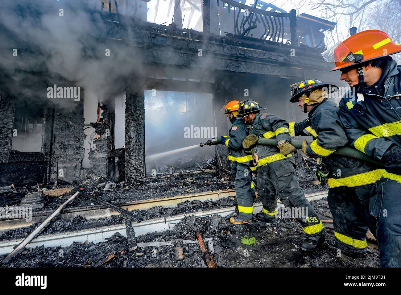 East Hampton firefighters hoses down hot spots inside the remains of a ...