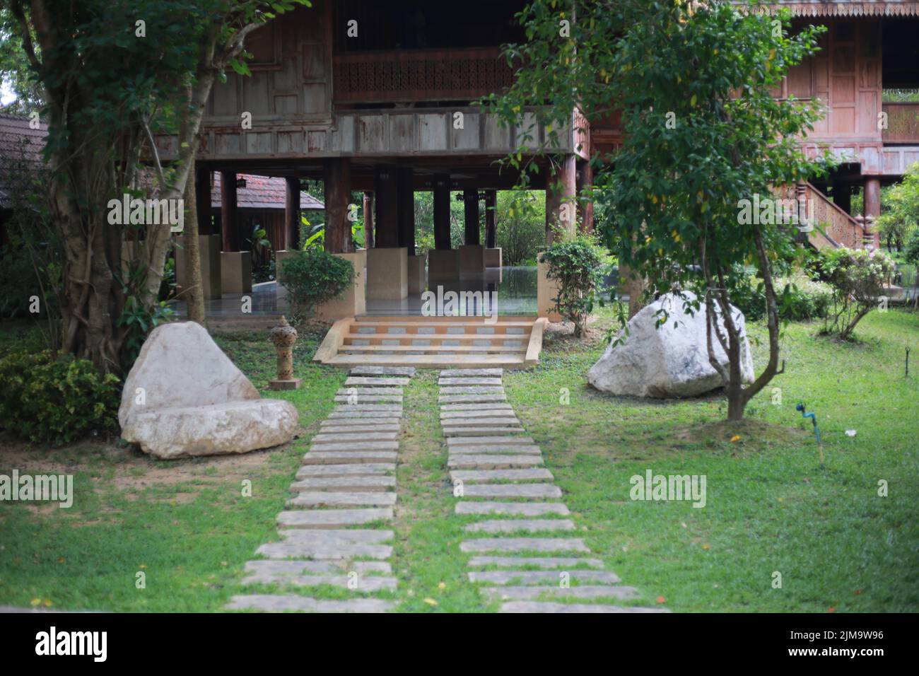 A beautiful green grassy garden of a wooden house with stone benches ...
