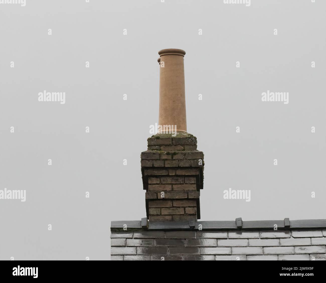 Brick stack with cream terra cotta chimney pots against grey sky and ...