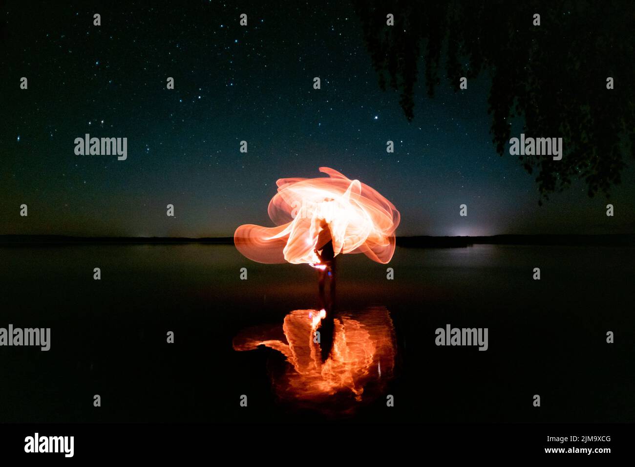 A long exposure shot of light trails being reflected on the lake under ...