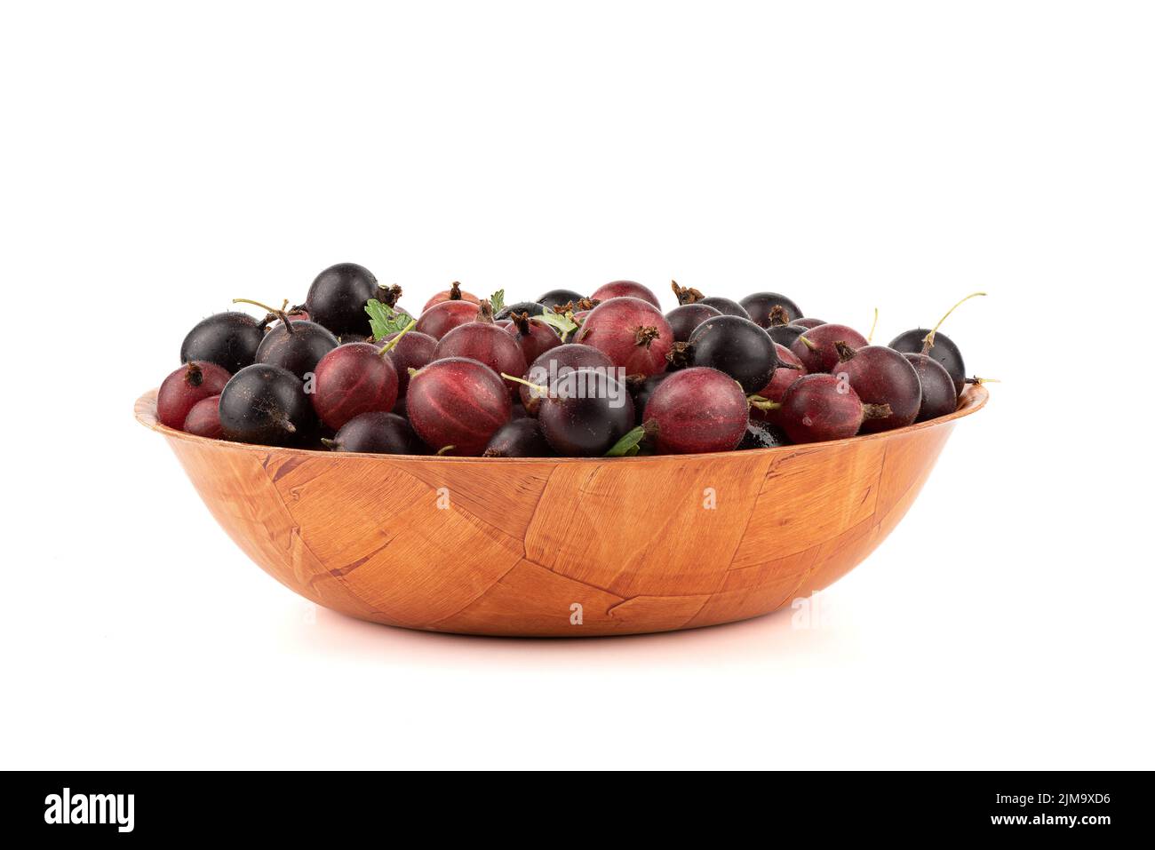 Red ripe gooseberries in a wooden bowl on a white background ...
