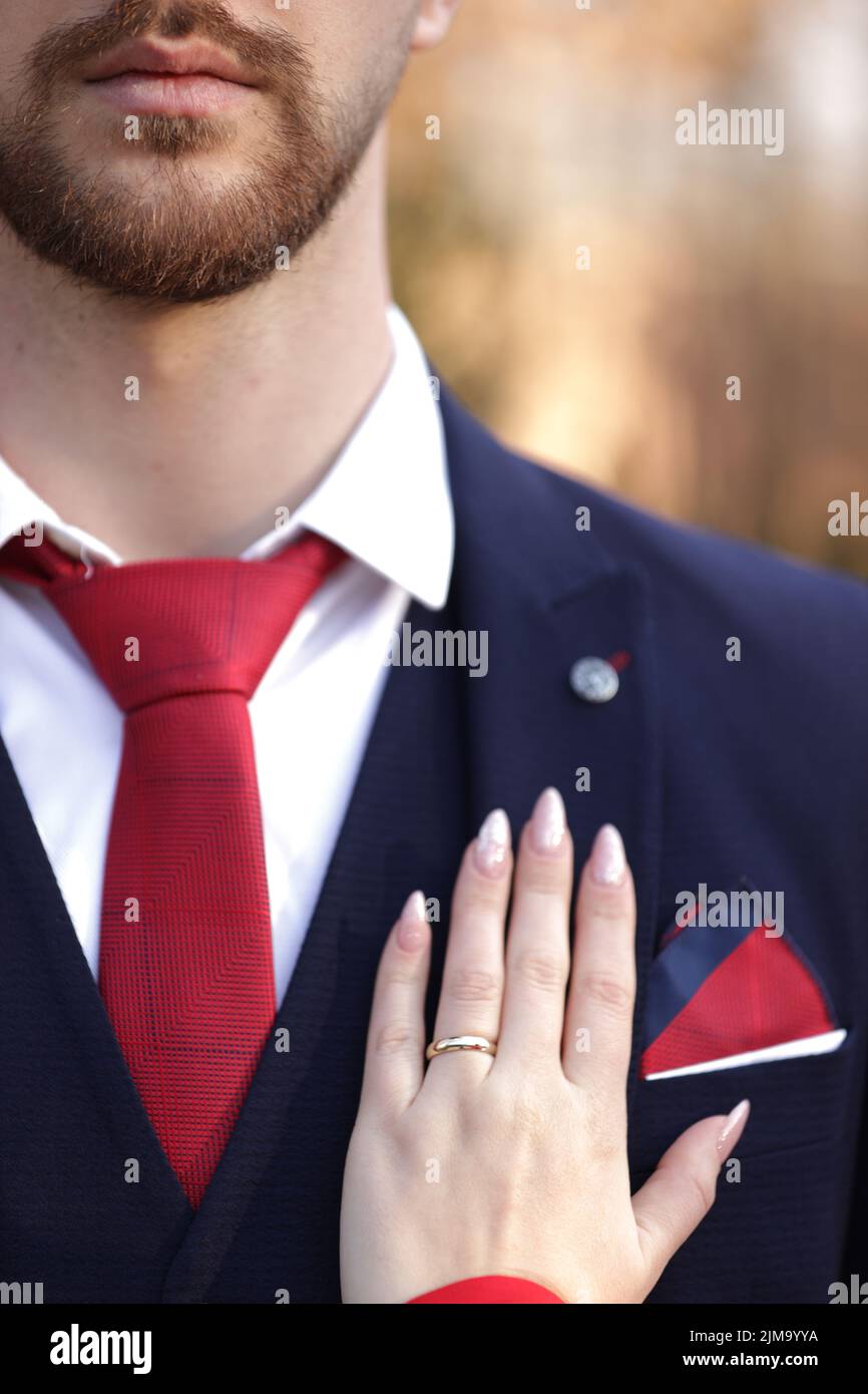 A vertical shot of the groom wearing smoking with the bride's hand put ...