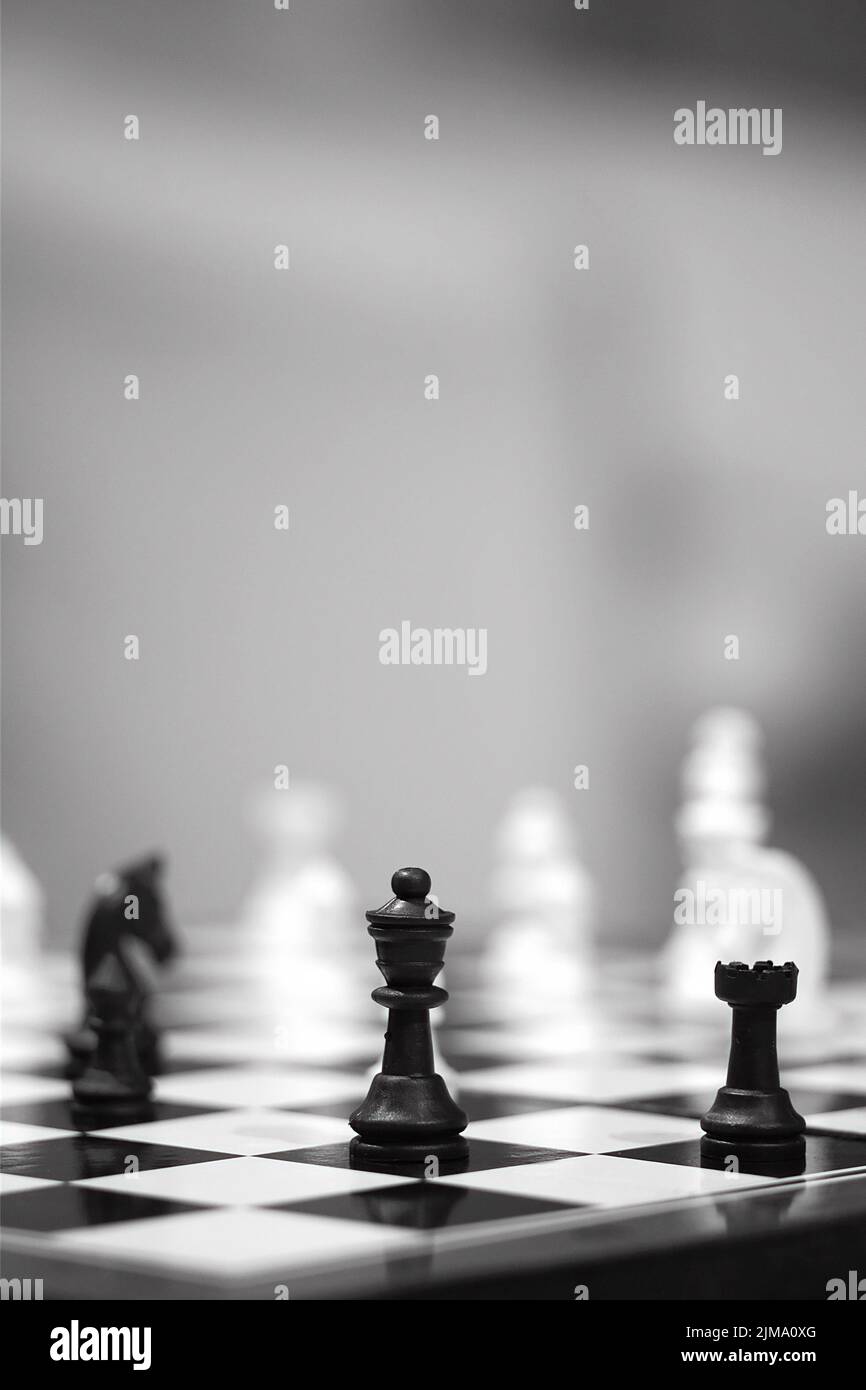 A vertical grayscale shot of chess pieces on a board Stock Photo - Alamy