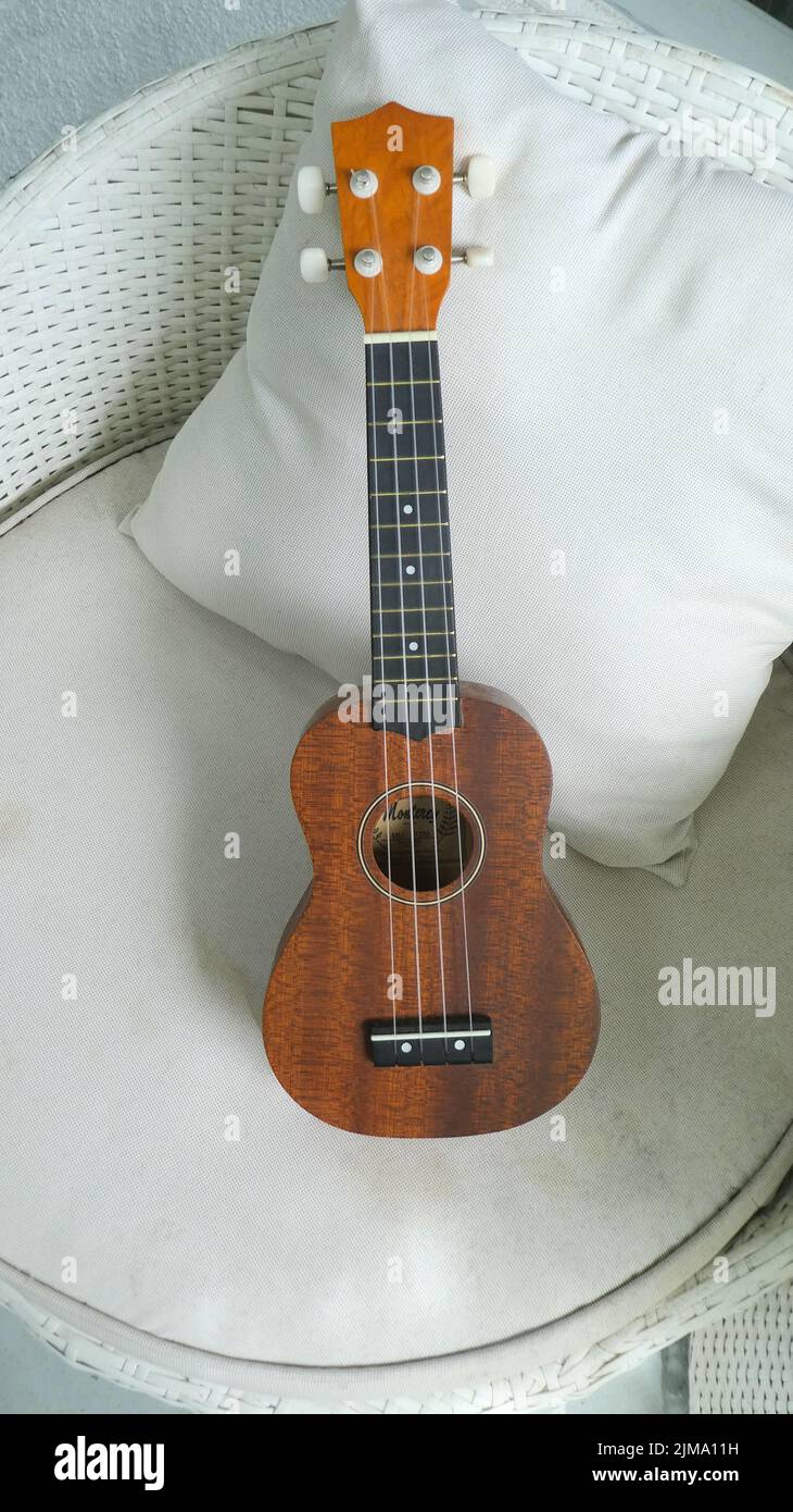 ukulele leaning upright against cushion on white chair Stock Photo - Alamy