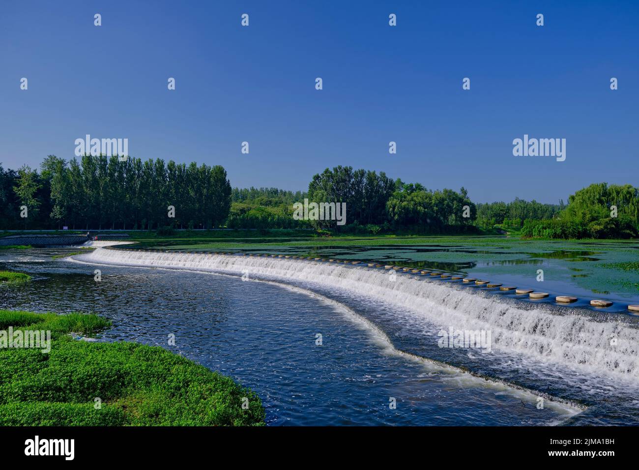 The beautiful park with artificial waterfalls surrounded by green ...