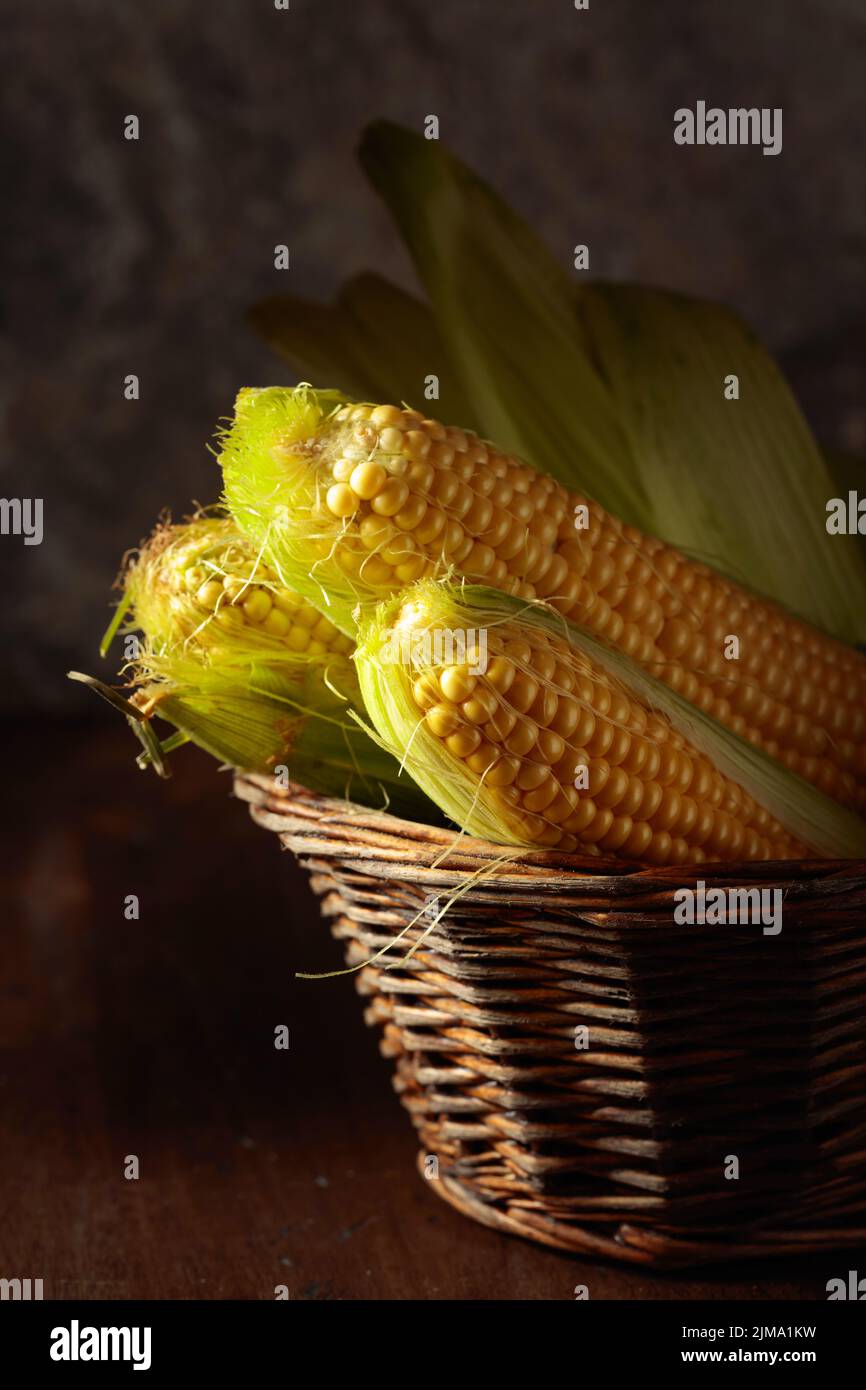 Fresh corn on cobs in a basket on a rustic wooden table Stock Photo - Alamy