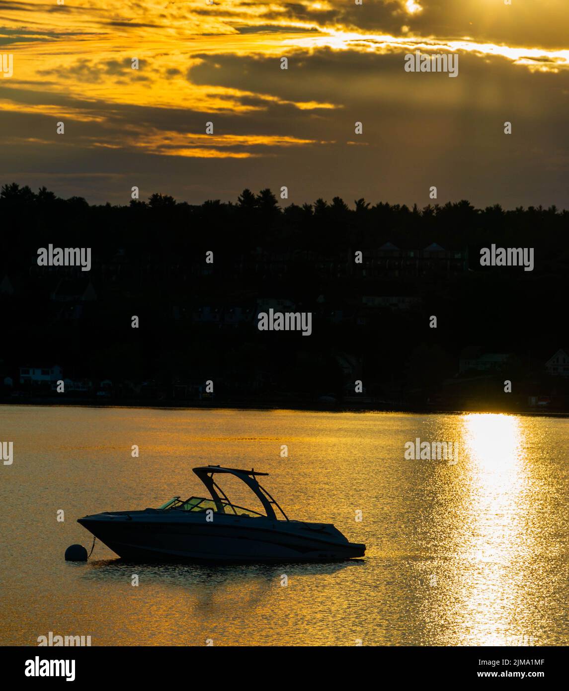 A boat in the sea at scenic sunset with trees in the background Stock ...