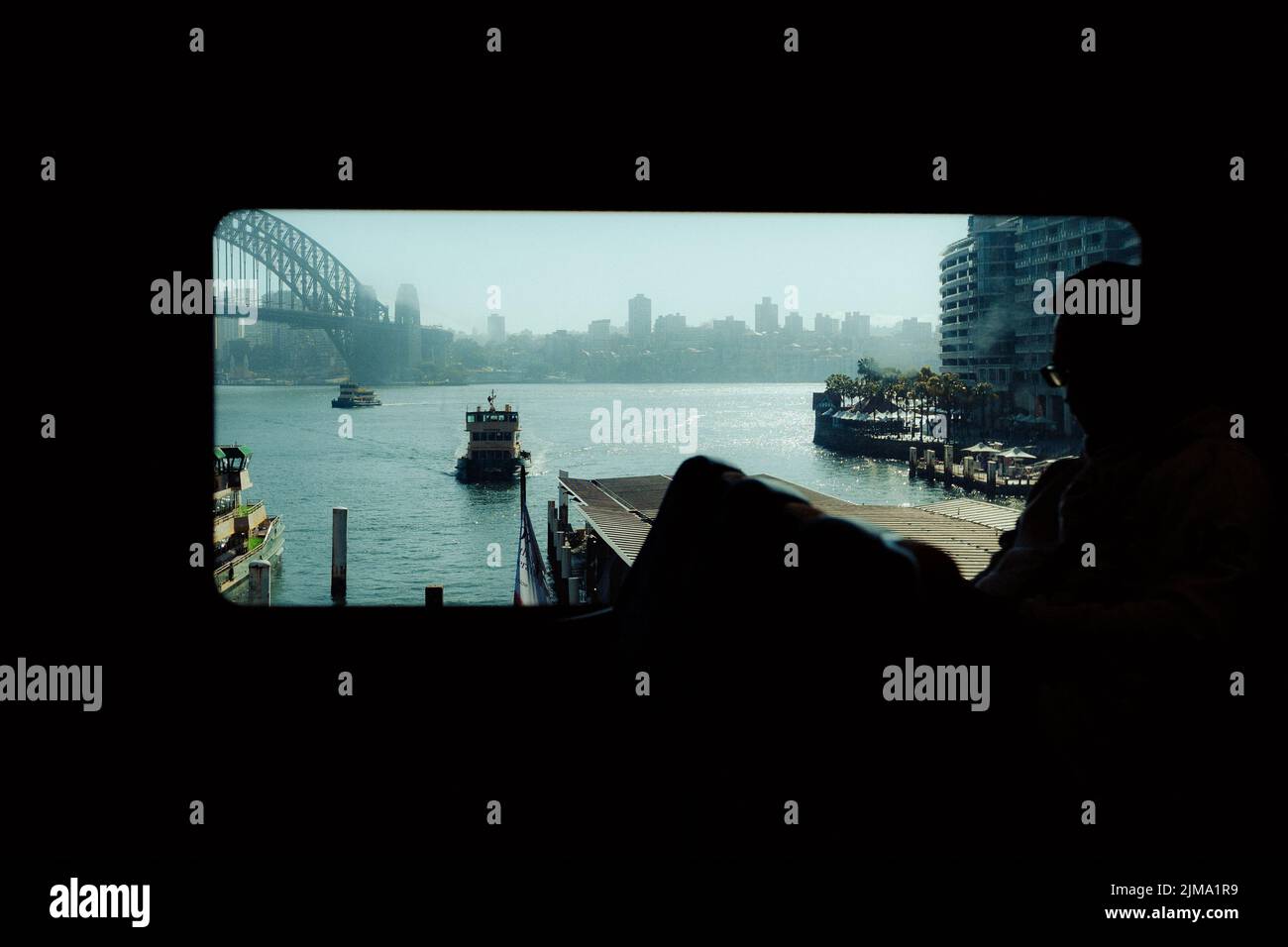 A back view of a man looking at the ships in the river behind the cabin ...