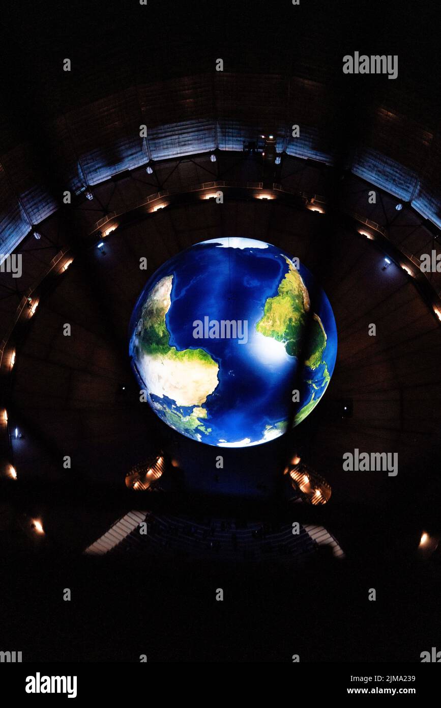 A vertical view of a glowing installation of the Earth in a tunnel ...