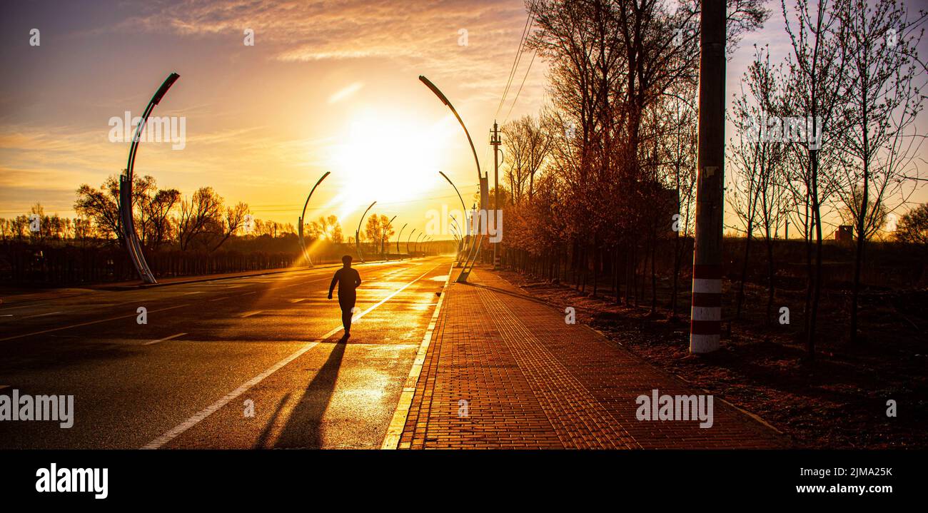 A person running in a long and empty road with street lights under a ...