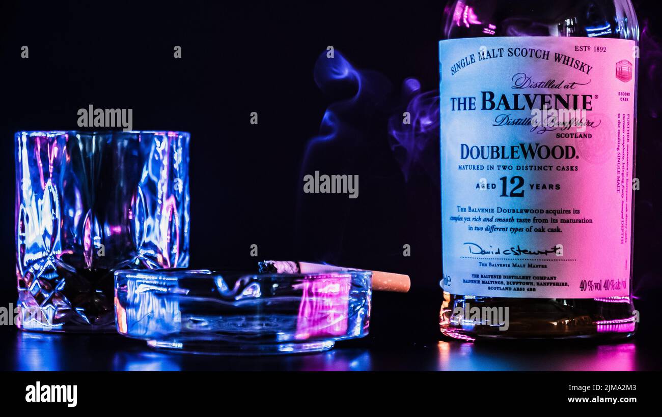 The Balvenie Bottle with a glass and cigarette isolated on a black ...