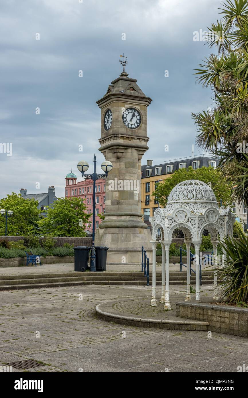 A vertical of a beautiful clock against colorful houses in Bangor ...