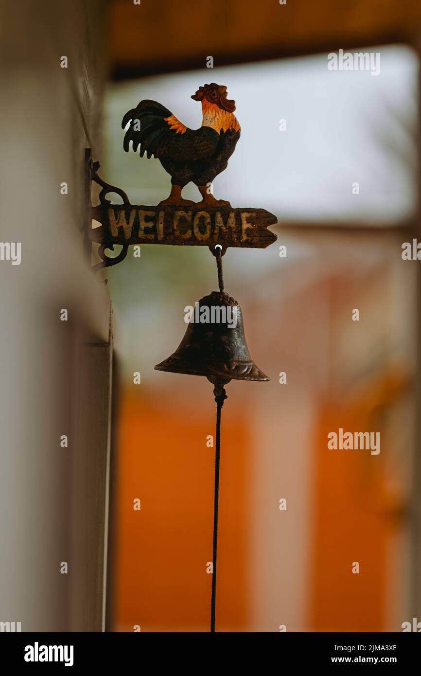 A vertical closeup of a metallic bell hanging from a door with a ...