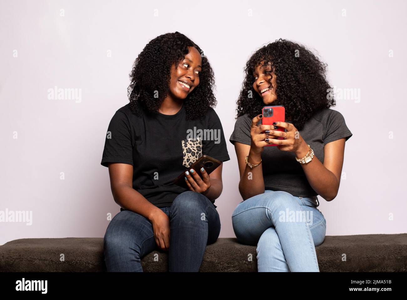 two black girls using their phones and talking Stock Photo - Alamy
