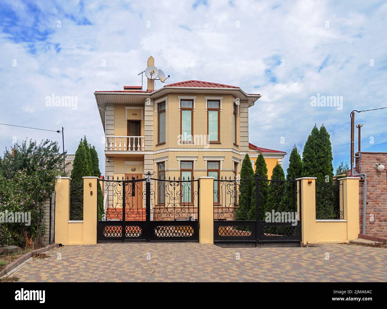 Beautiful yellow cottage behind the metal gate Stock Photo - Alamy