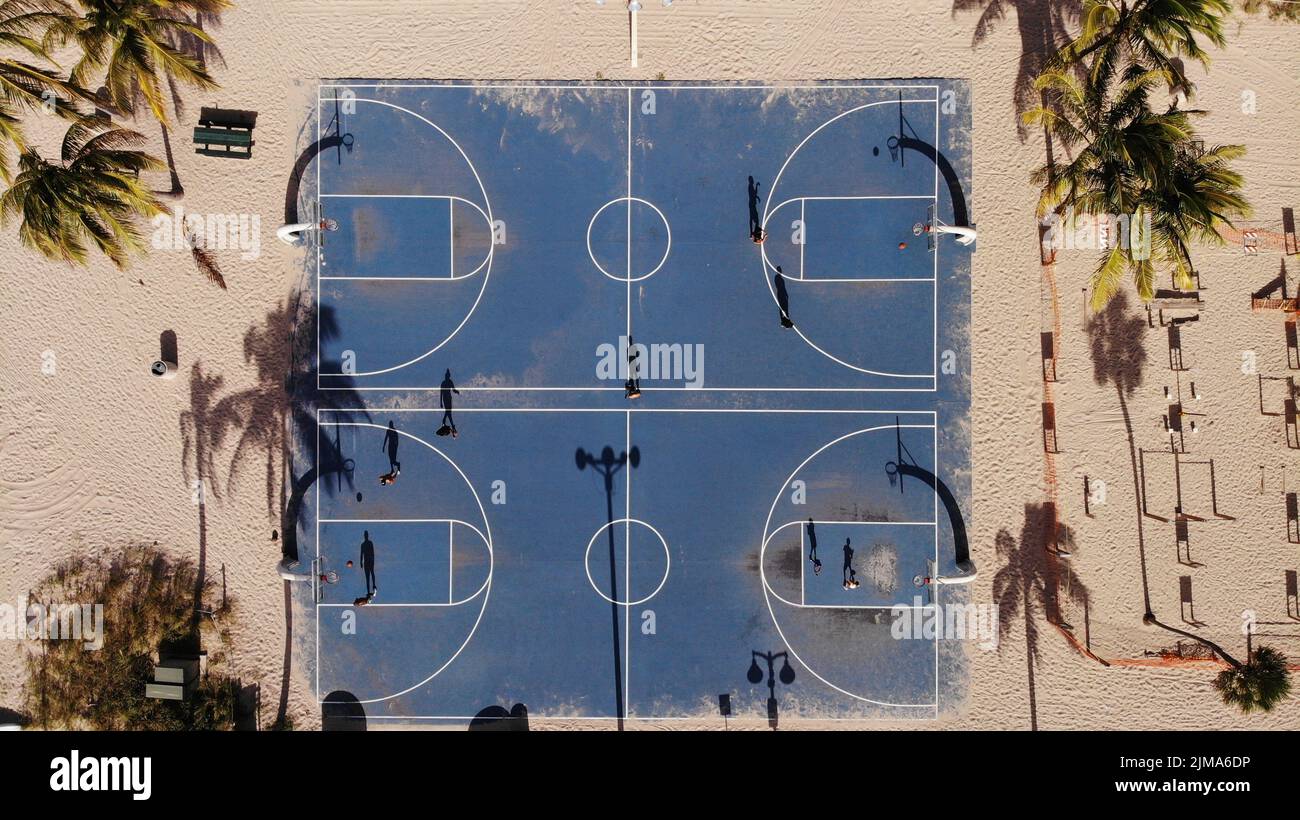 An aerial top view of people playing on blue basketball courts on a ...