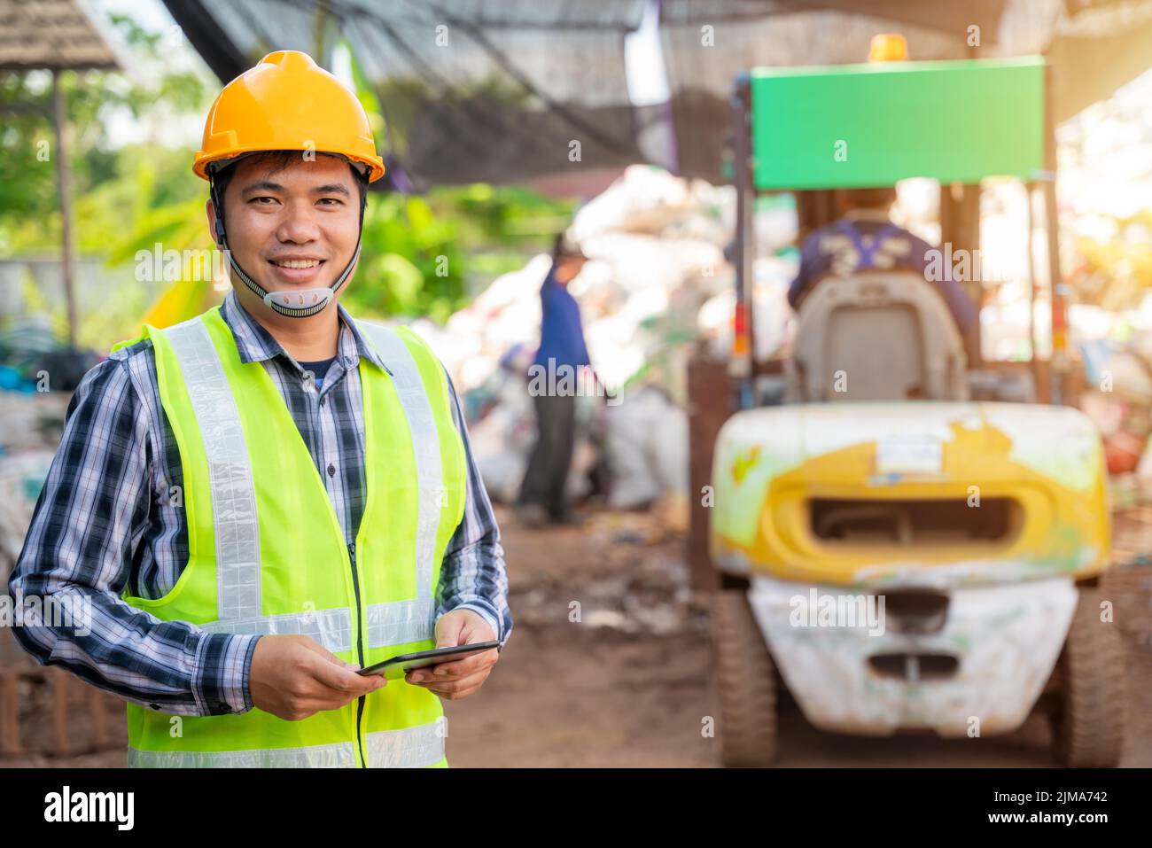 Asian workers in recycling factory with a forklift on the background ...