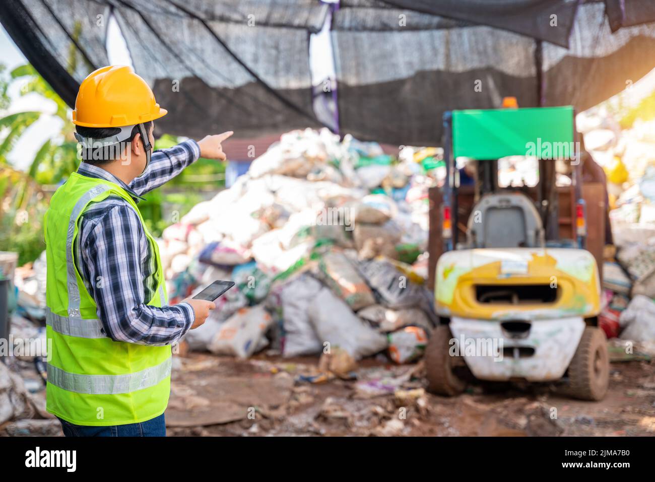 Asian foreman working in recycling factory and holding tablet and ...