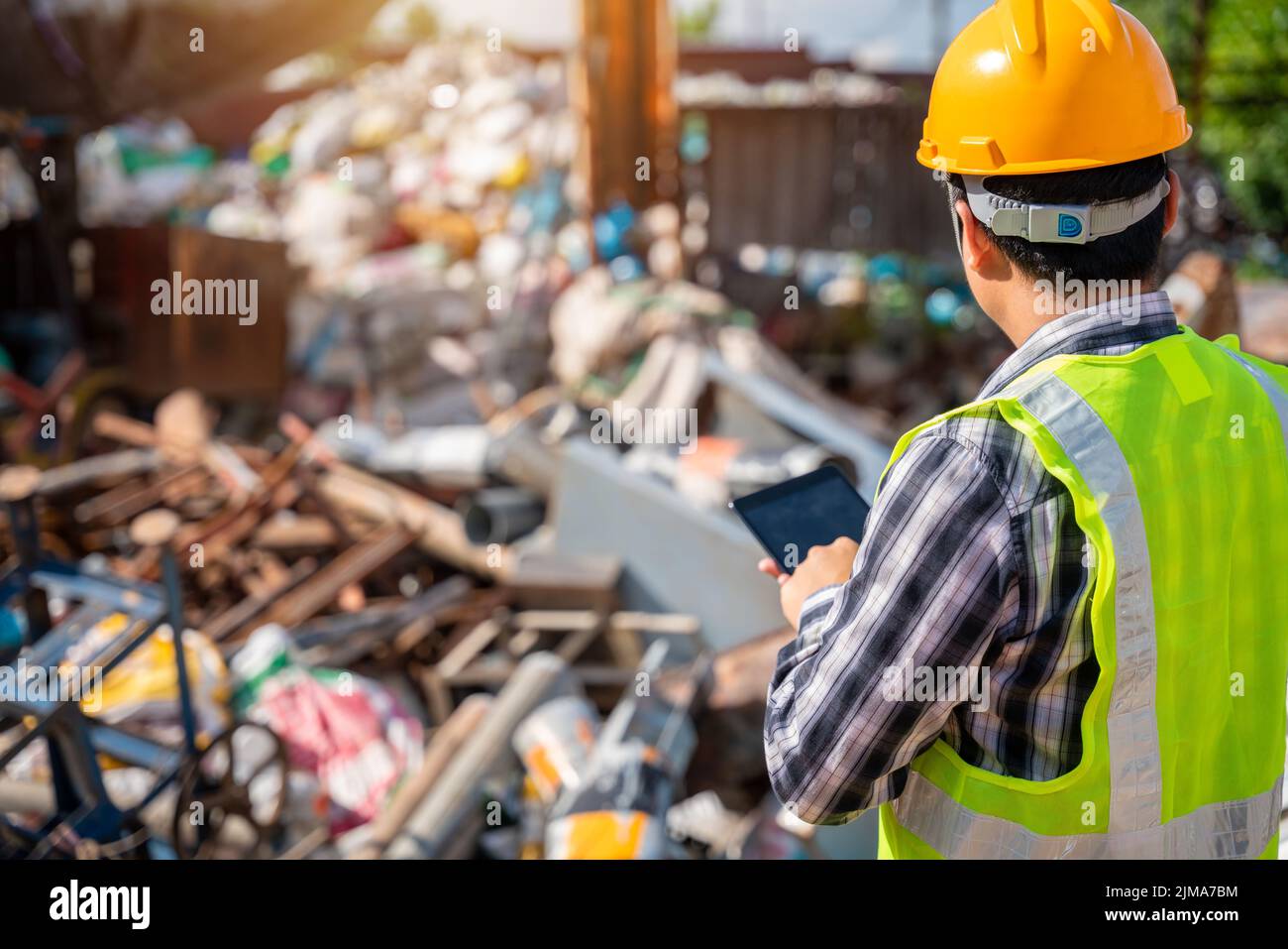 A worker holding a tablet looks at a pile of steel for recycling at a ...