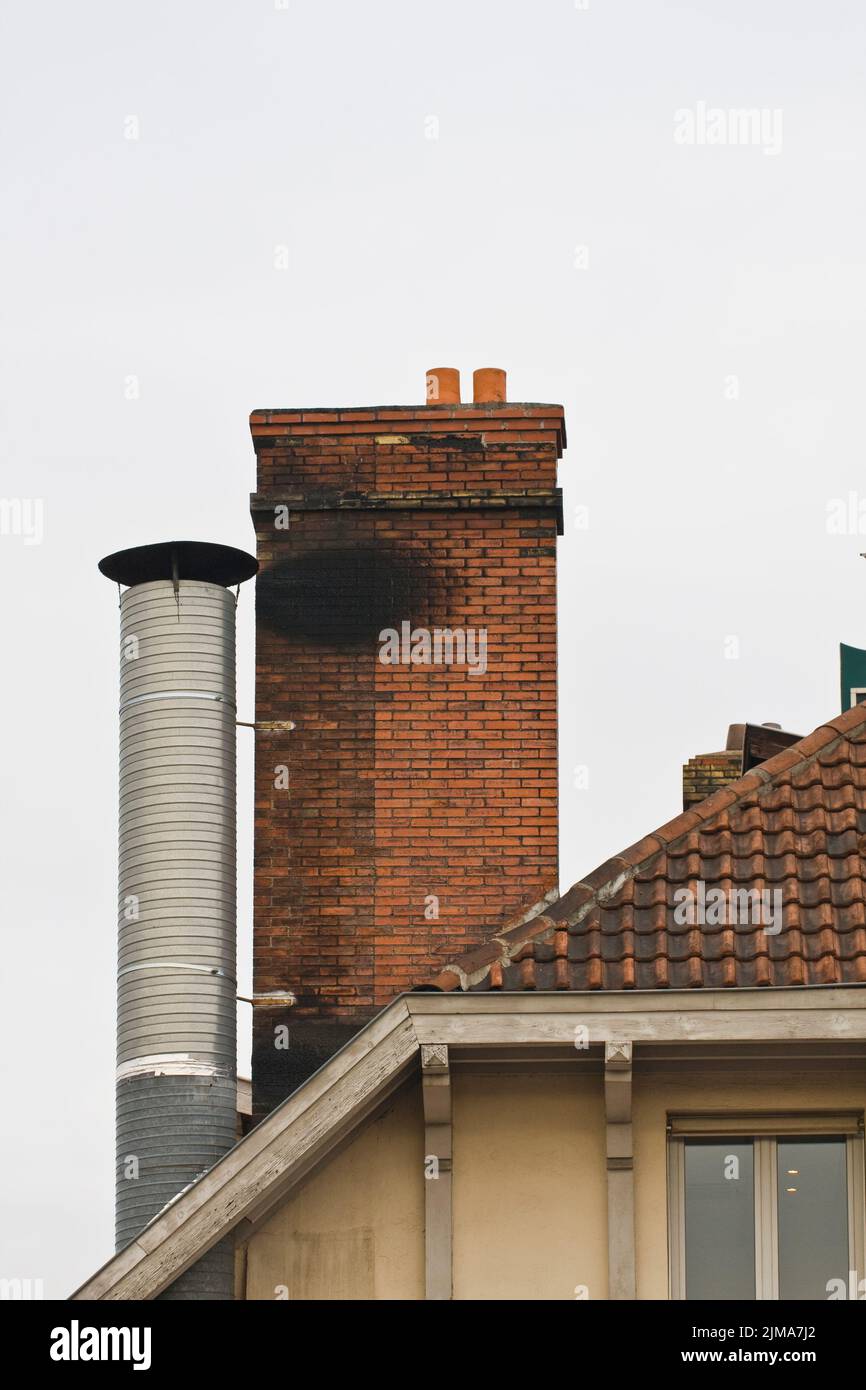Red brick chimney and metal chimney on tiled roof Stock Photo - Alamy