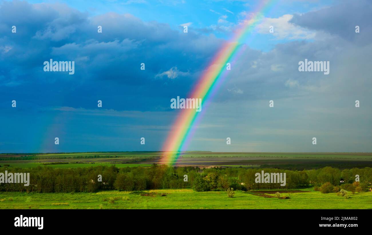 The Rainbow over a field after thunderstorm Stock Photo - Alamy