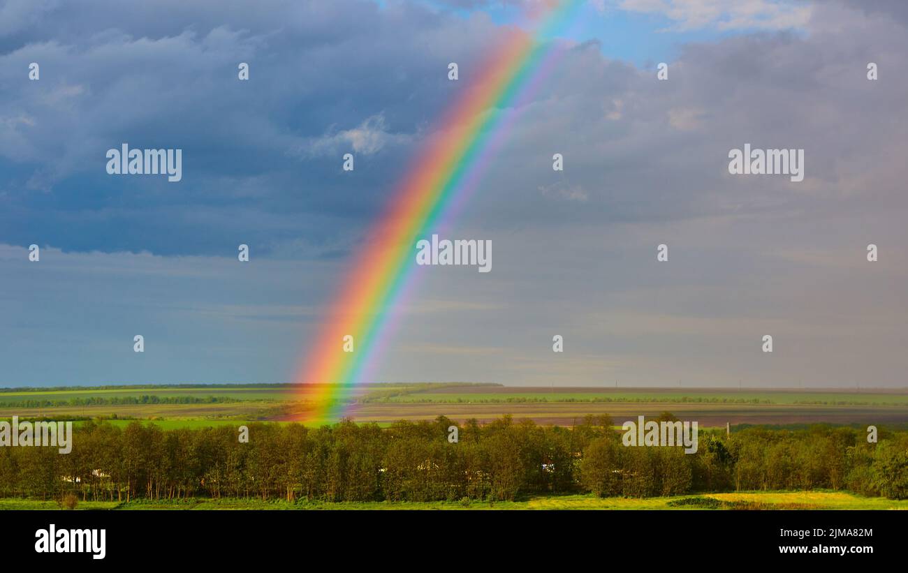 The Rainbow over a field after thunderstorm Stock Photo - Alamy