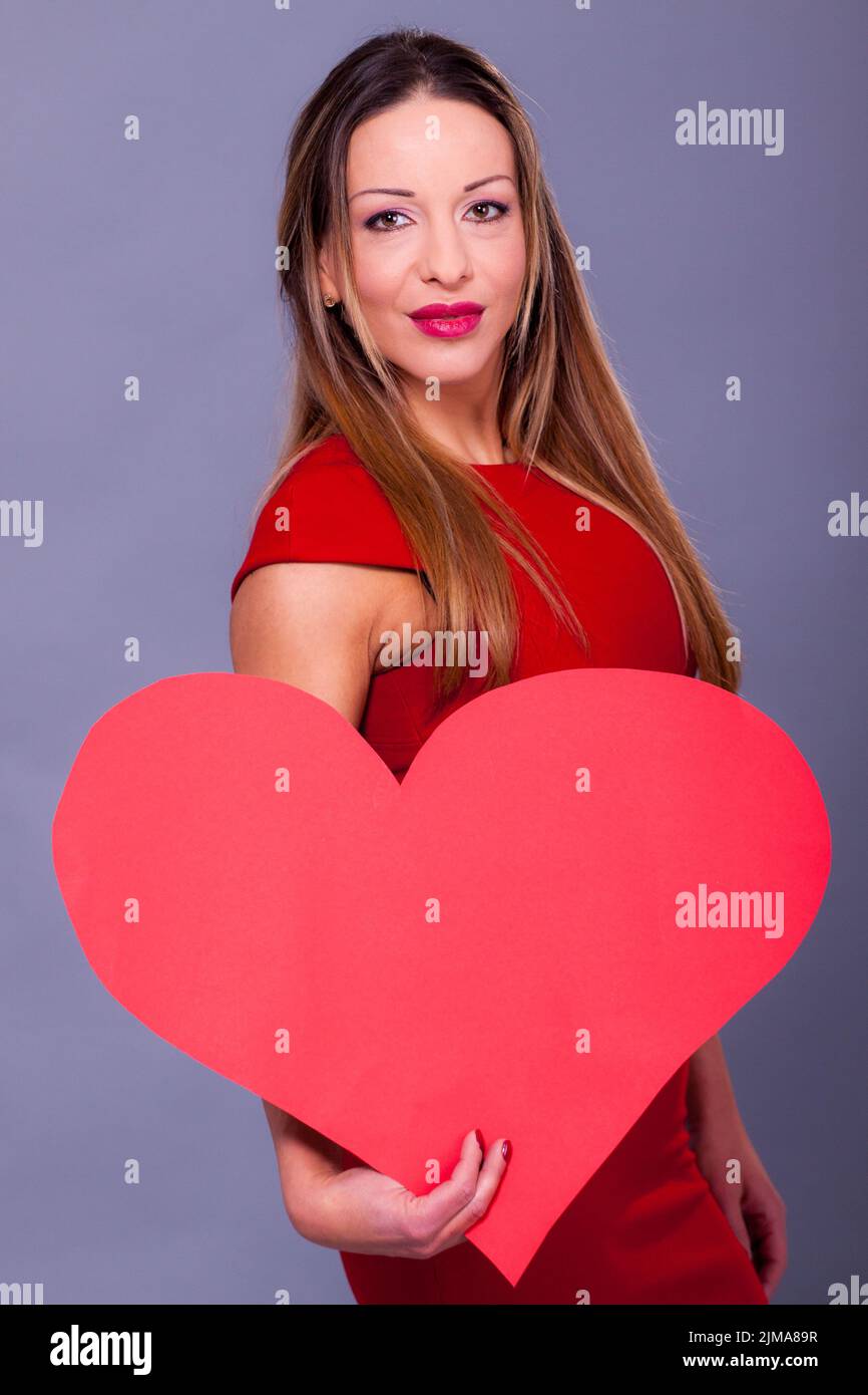 Woman wearing red dress holding big heart sign love symbol Stock Photo ...