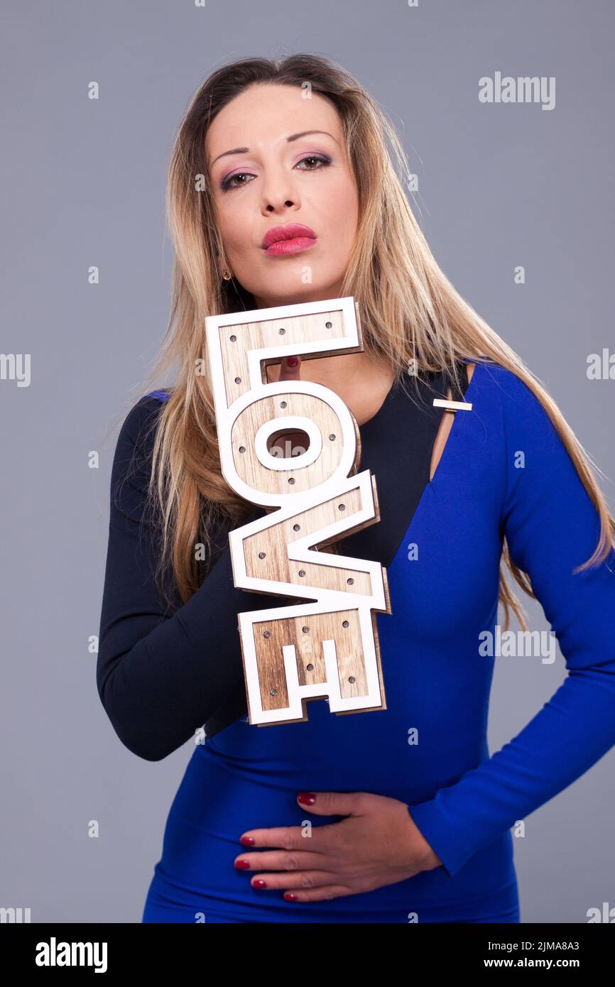 Woman wearing blue dress holding sign love symbol Stock Photo - Alamy