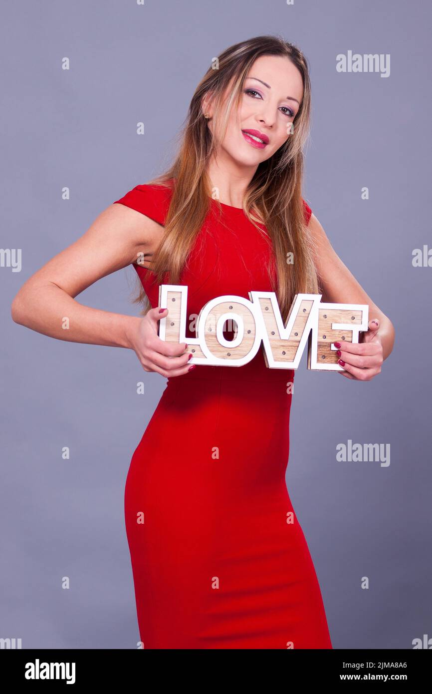Woman wearing red dress holding sign love symbol Stock Photo - Alamy