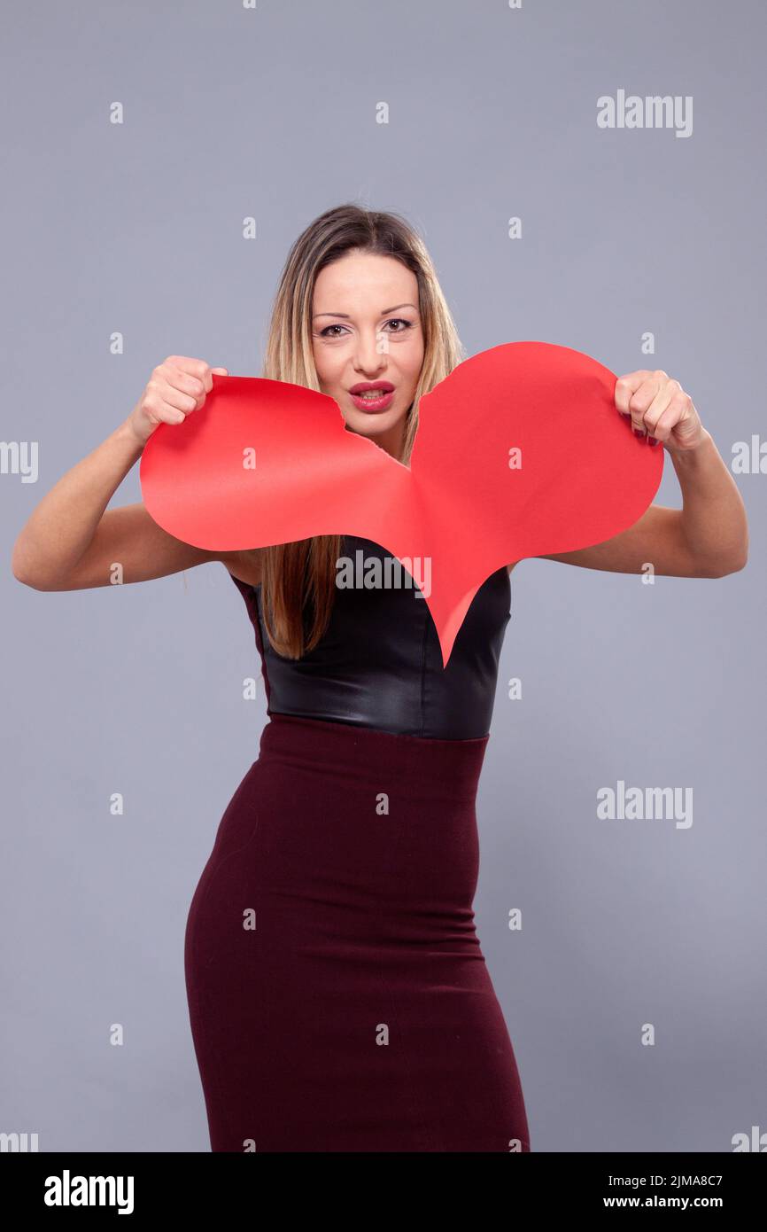 Woman wearing red dress holding big heart sign love symbol Stock Photo ...