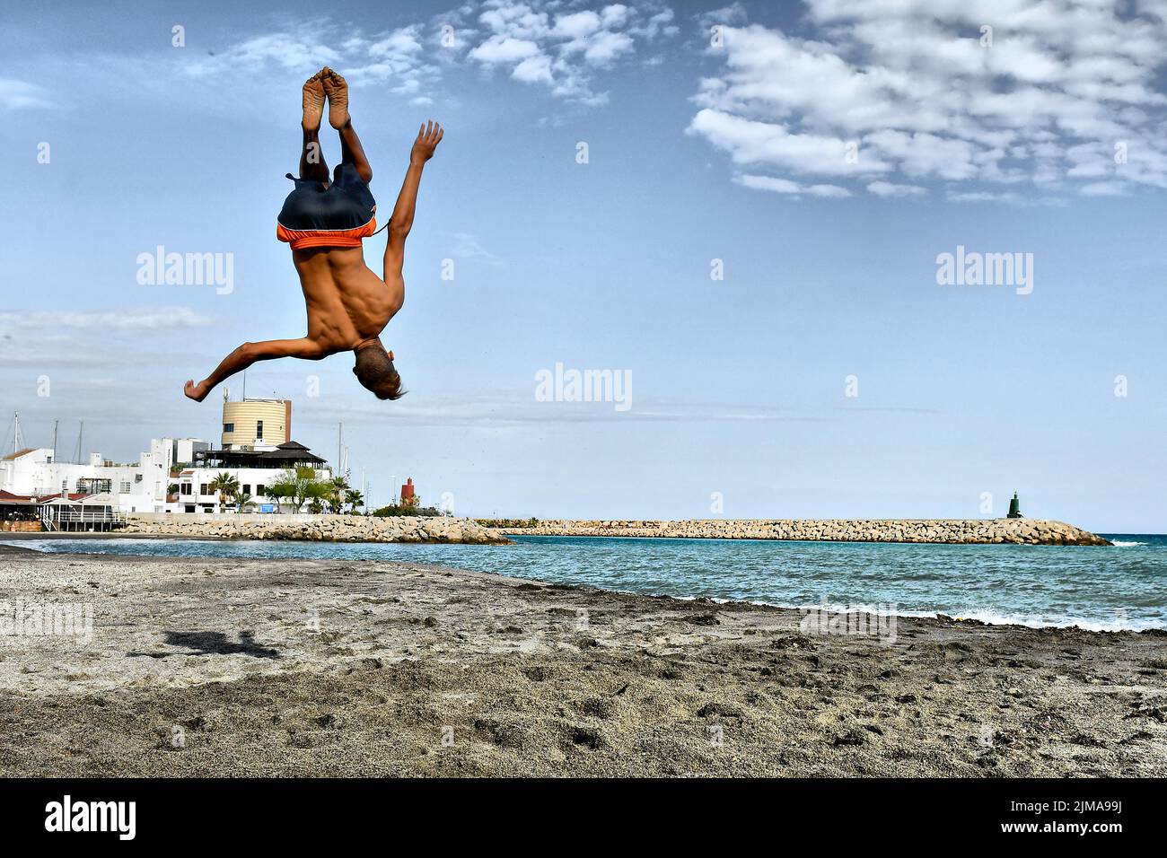 Young man doing backflips somersaults in the sand Stock Photo - Alamy