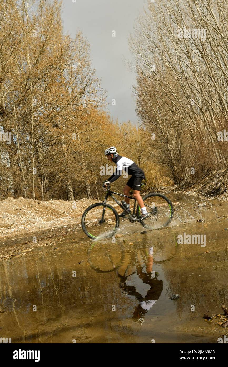 Cyclist crosses a stream with his bike and churns up the water Stock ...