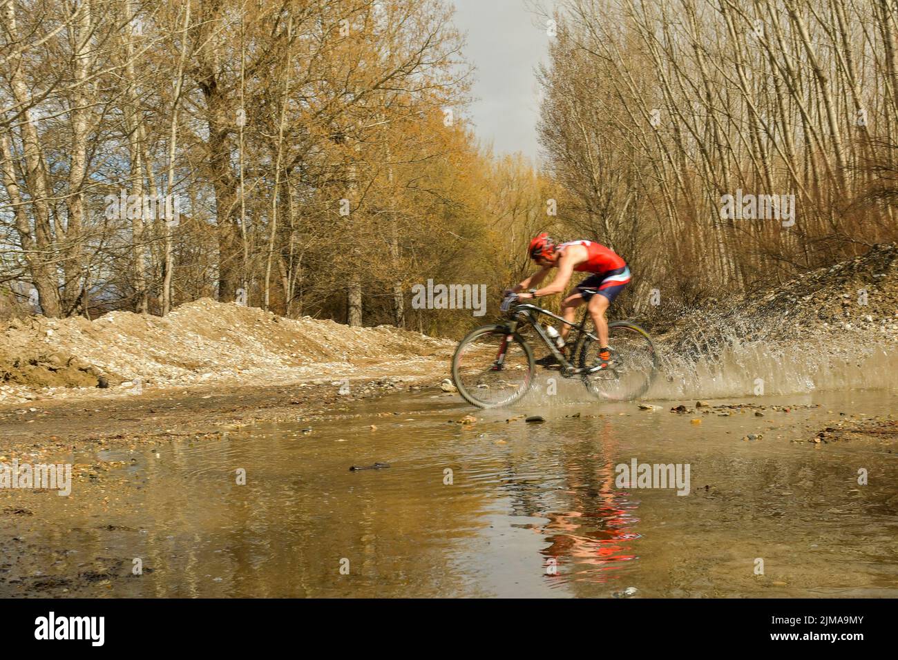 Cyclist crosses a stream with his bike and churns up the water Stock ...
