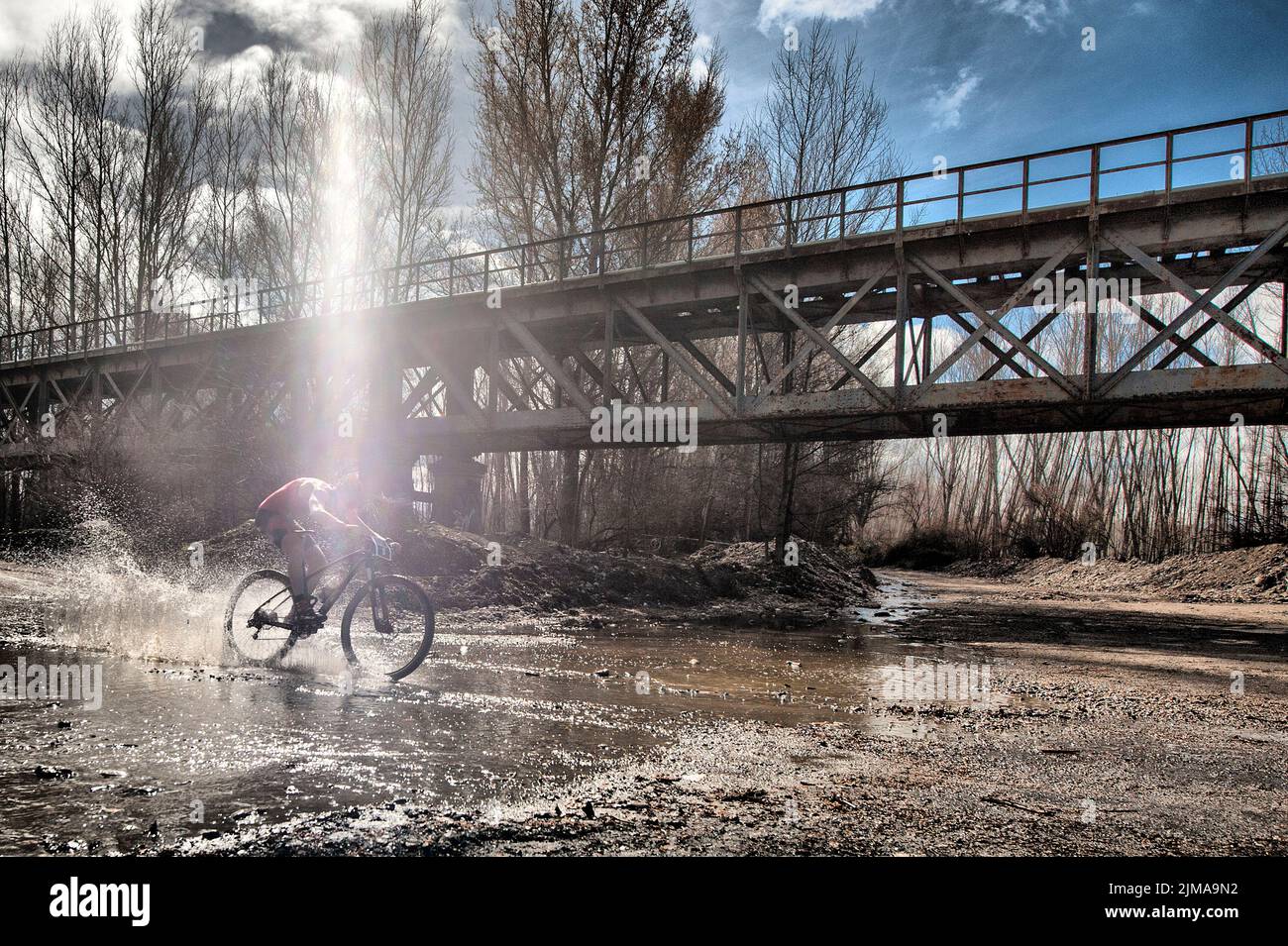 Cyclist crosses a stream with his bike and churns up the water Stock ...