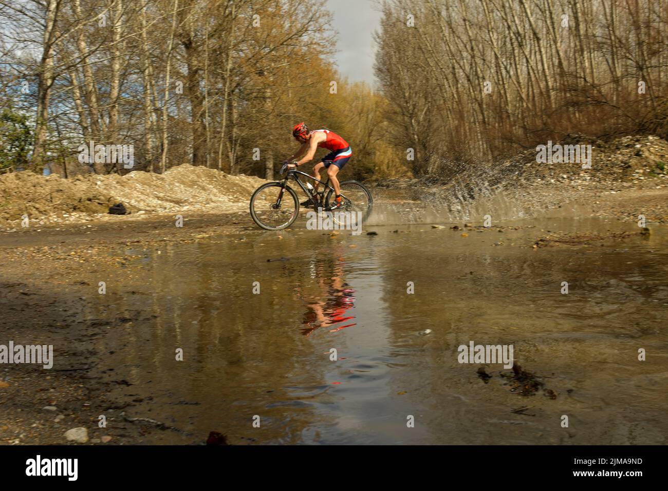 Cyclist crosses a stream with his bike and churns up the water Stock ...