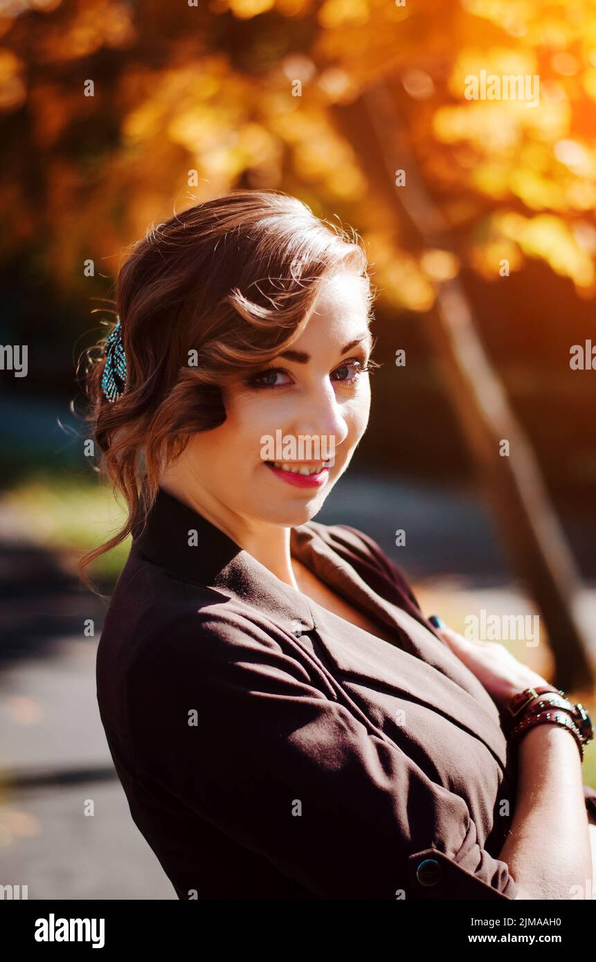 Portrait of smart girl with old-fashioned hairstyle outdoor in brown ...