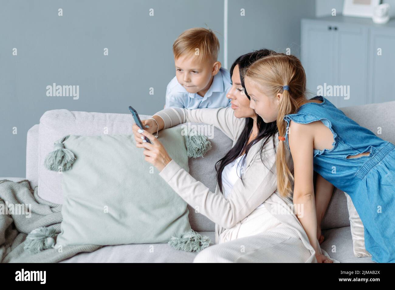 mom with two kids watching videos on her smartphone Stock Photo - Alamy