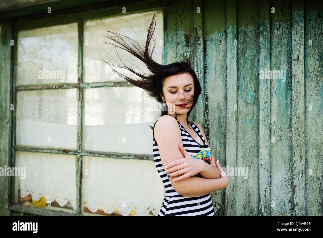 Brunette Model Girl With Hair On The Air Wearing On Dress With Stripes