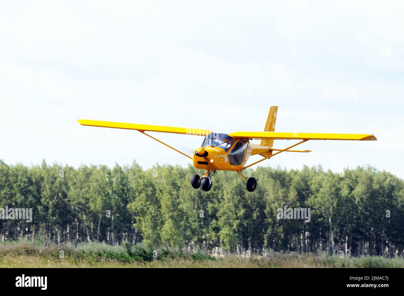 Private propeller-driven airplane landing over green trees Stock Photo ...