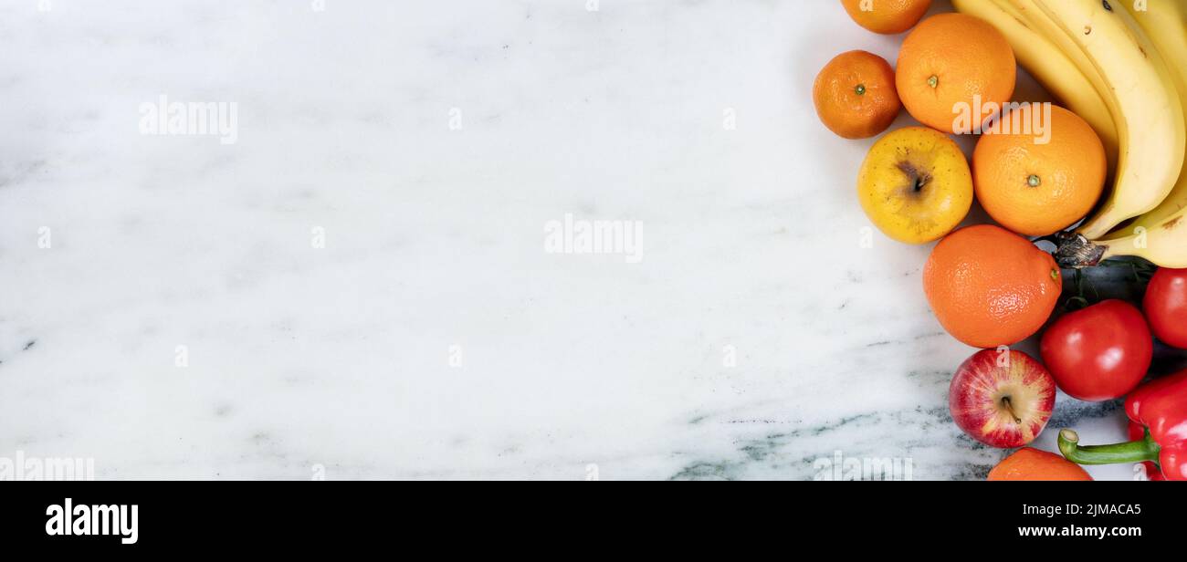 Fresh fruit and vegetables forming border on right side of marble stone ...